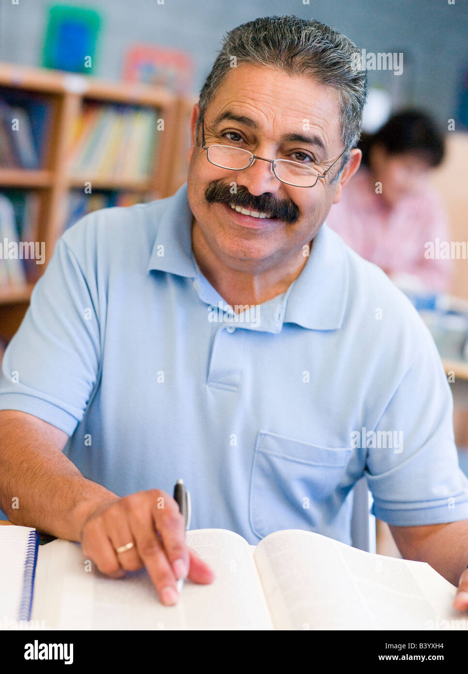 Man sitting in library with a book and notepad (selective focus Stock ...
