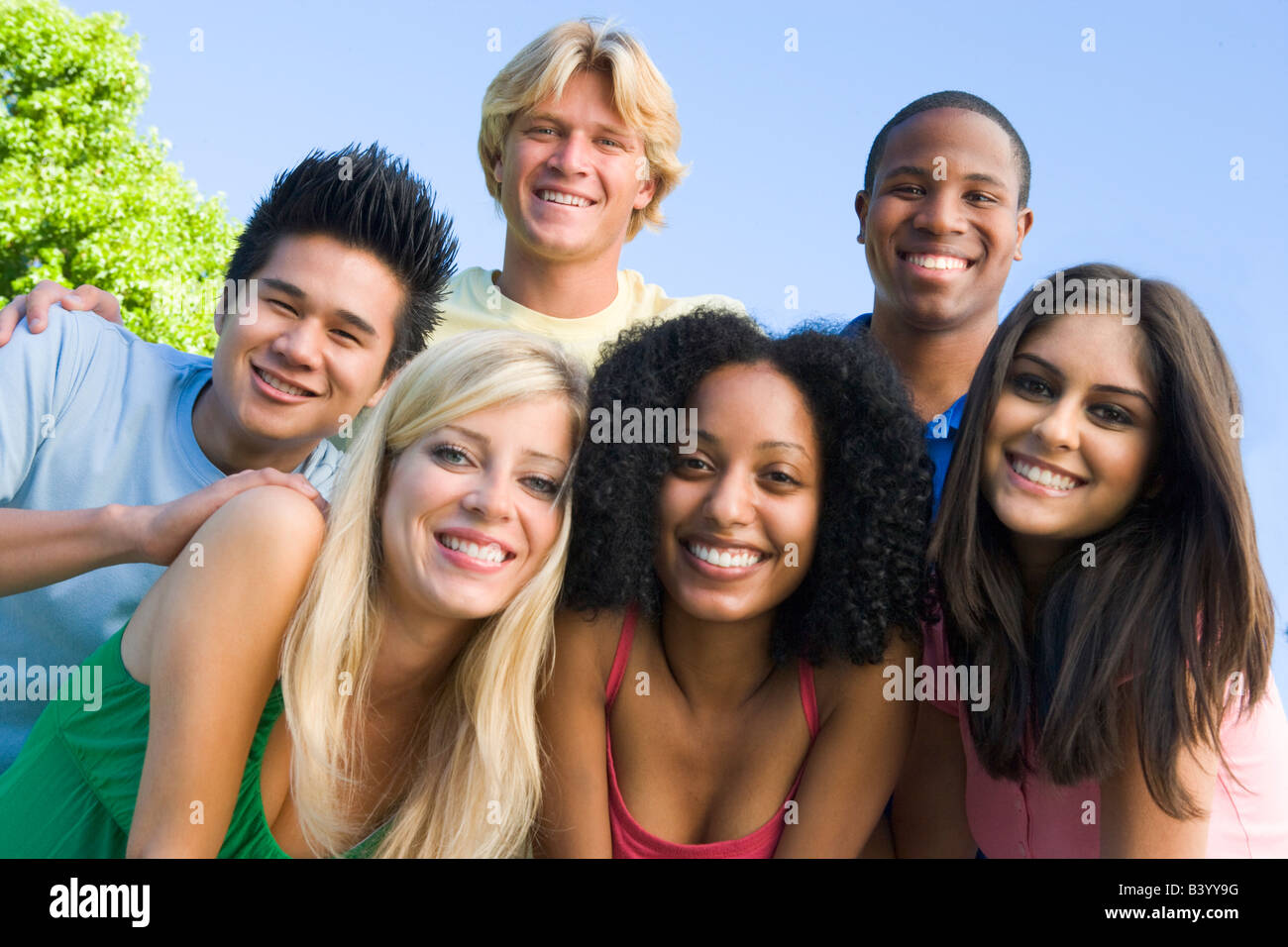 Six people outdoors huddling over camera Stock Photo - Alamy