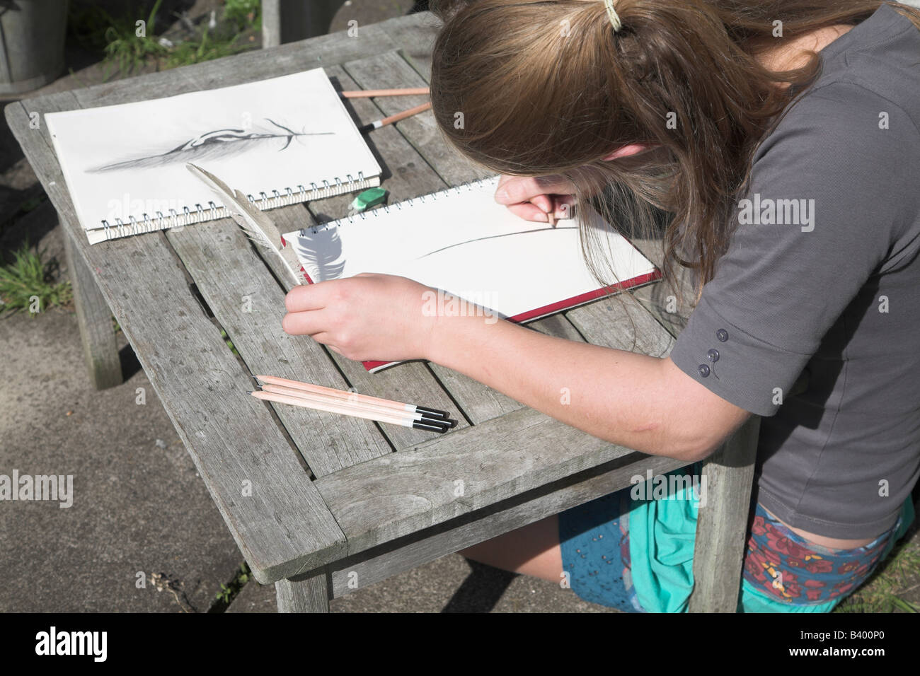 Teenage girl doing her art homework drawing a feather Stock Photo - Alamy
