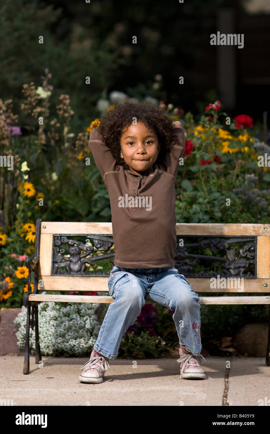 a young girl sitting on a bench with her arms behind her head Stock ...