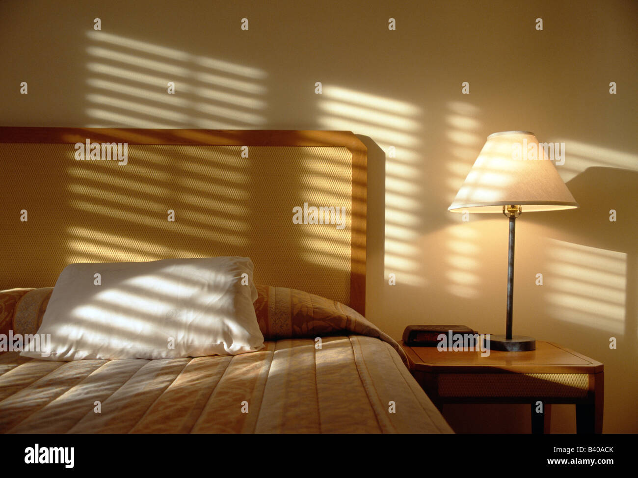 Sunlight casting interesting shadows on the bed, table and lamp in a ...