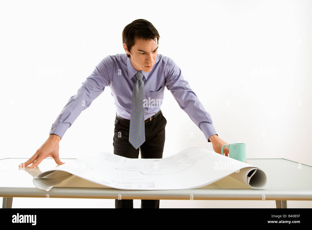 Asian business man standing looking over blueprints Stock Photo - Alamy
