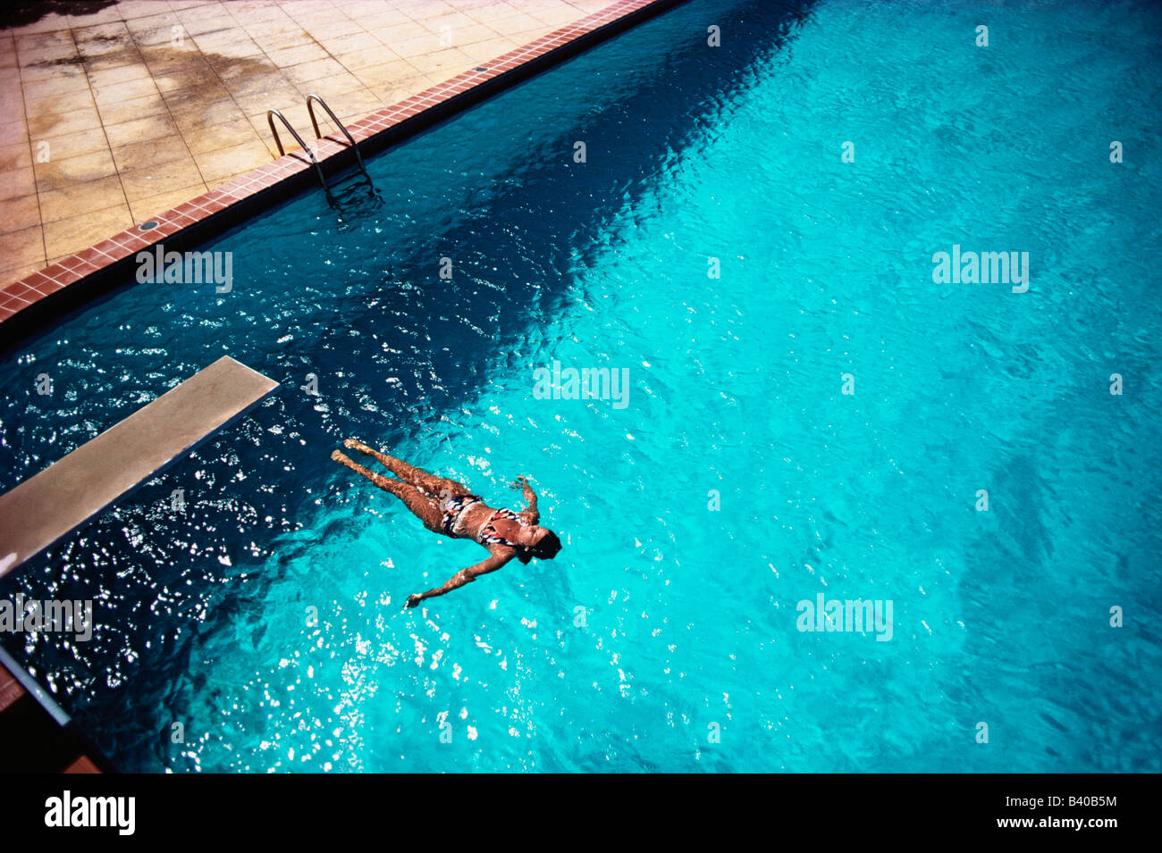 Woman floats in a clear blue swimming pool Stock Photo - Alamy