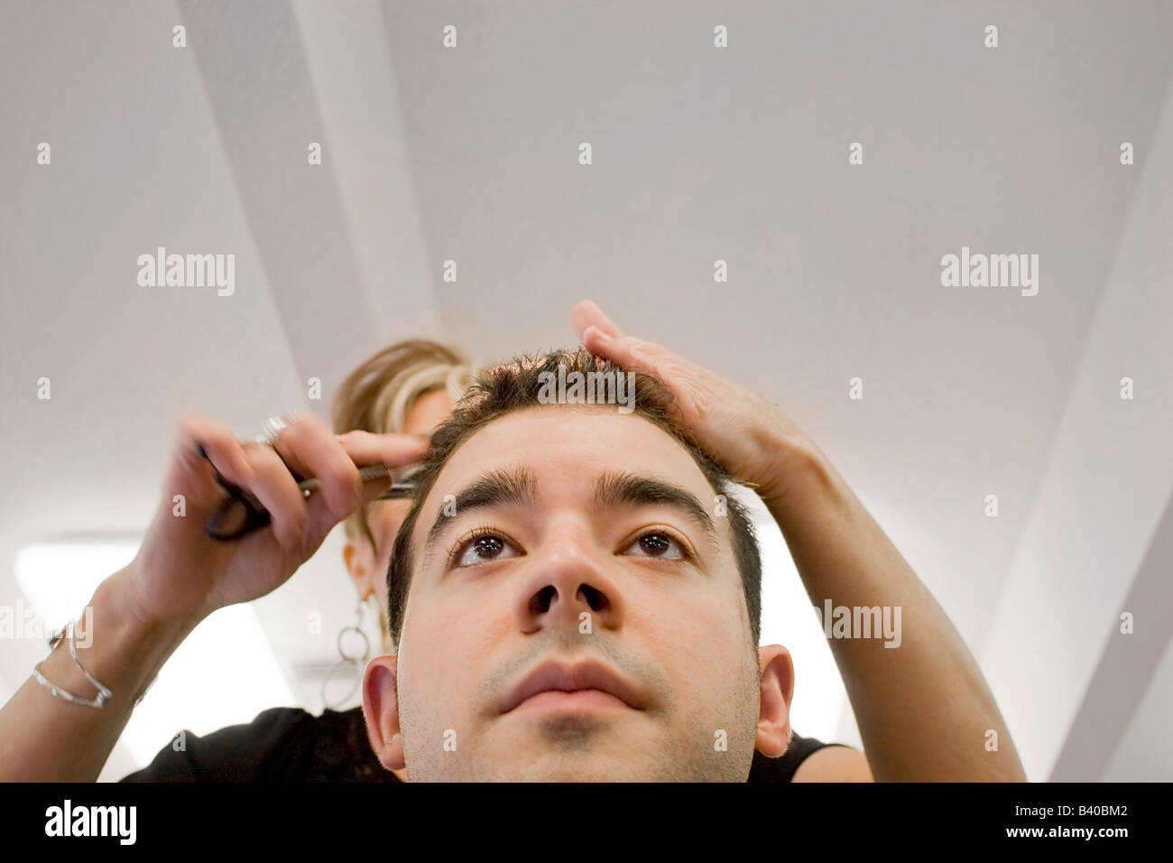 A young man getting his hair cut by a hairdresser at the salon Stock ...