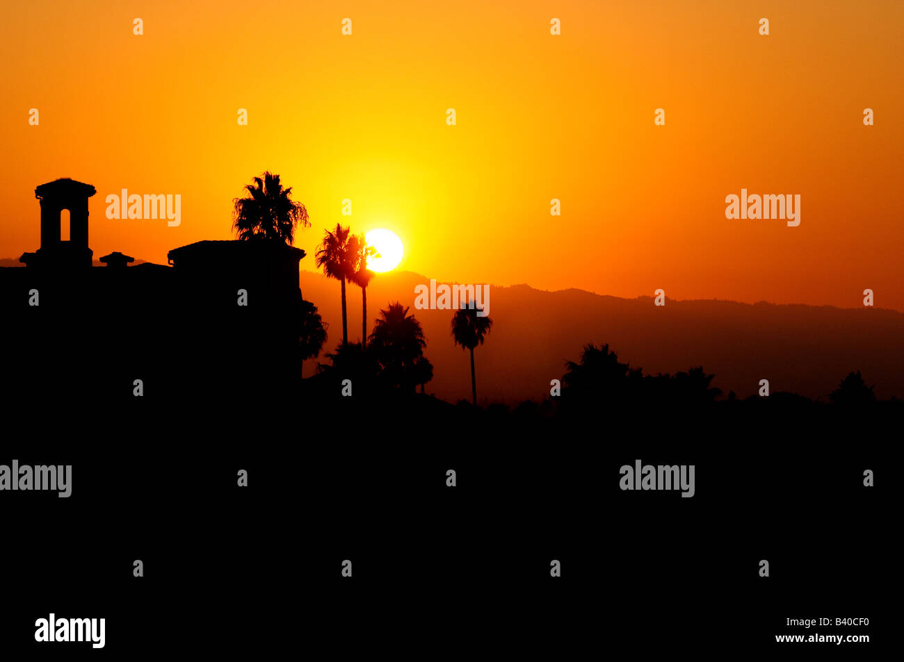 Sunset with buildings mountain range and Palm Trees medium wide view ...