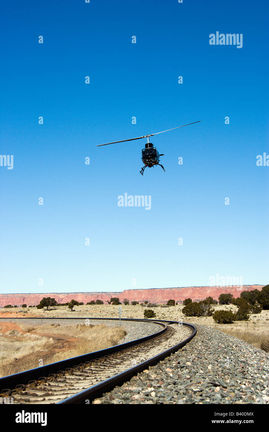 Low angle shot of helicopter flying over train tracks Stock Photo - Alamy