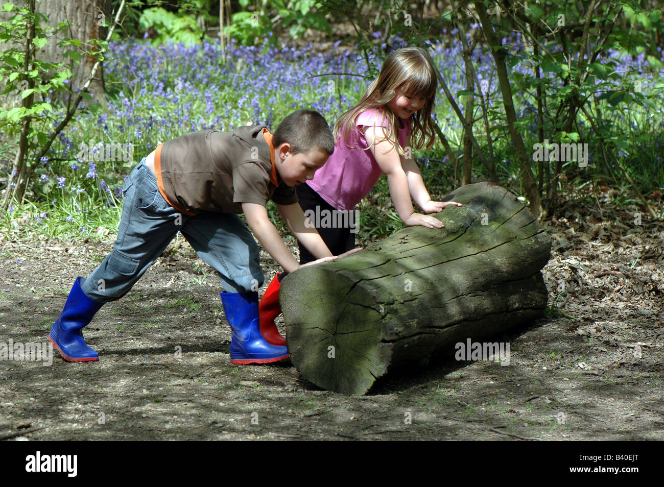A boy and girl trying to roll a log Stock Photo - Alamy