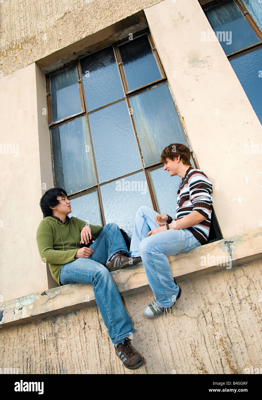 Two teenage boys sitting on window sill Stock Photo - Alamy