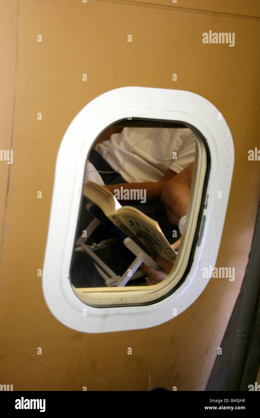 view from outside of commercial airplane window, a passenger reading a ...