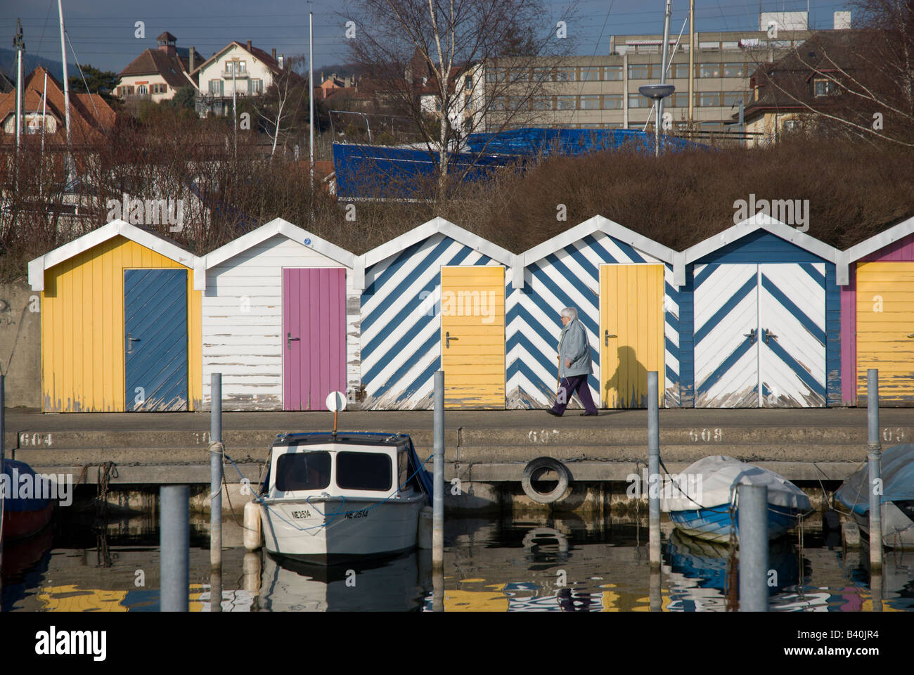 Old woman walks past brightly colored fishing shacks that line the ...