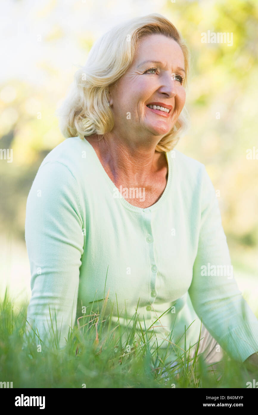 Woman sitting outdoors smiling Stock Photo - Alamy