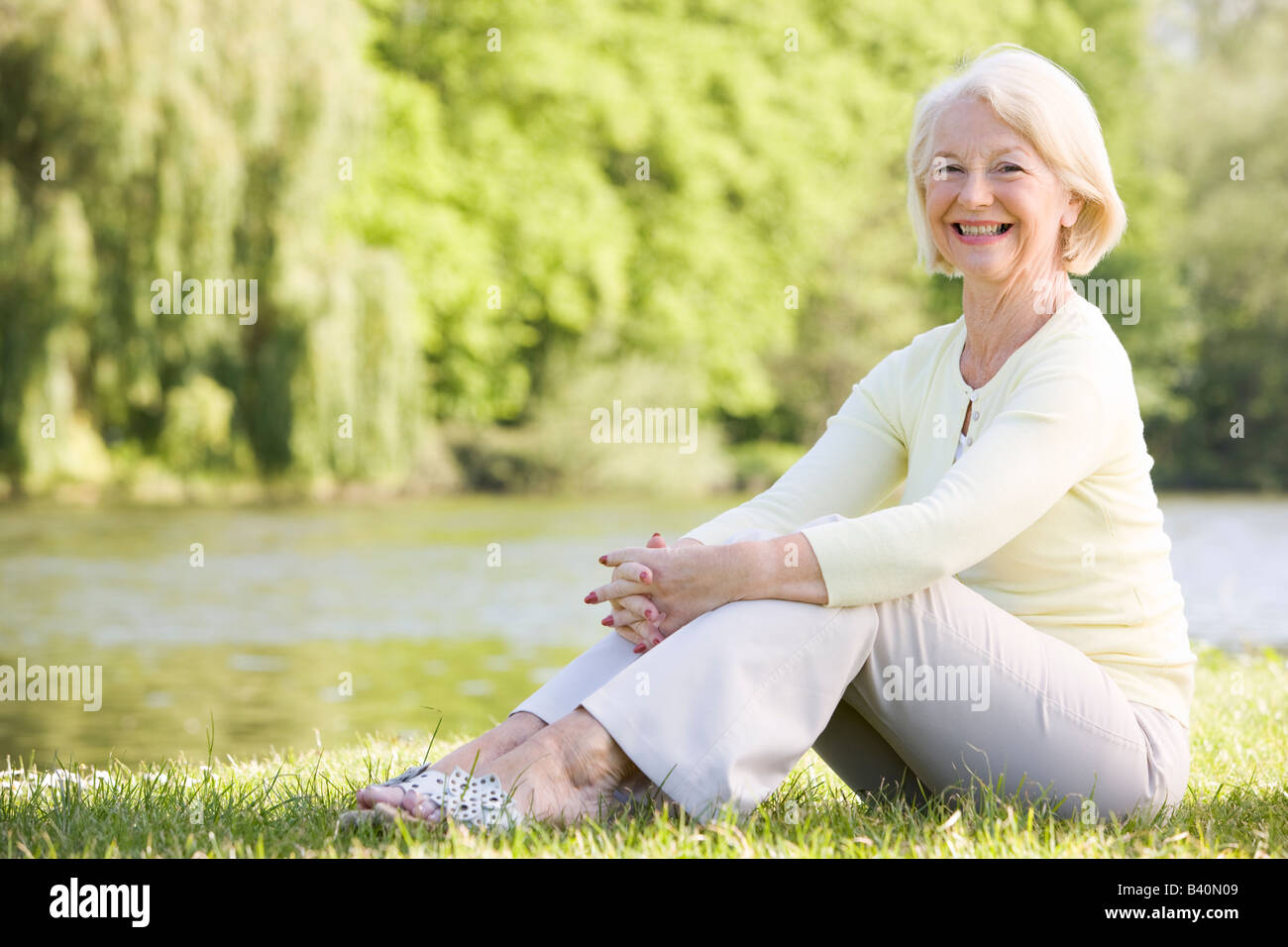 Woman outdoors at park by lake smiling Stock Photo - Alamy