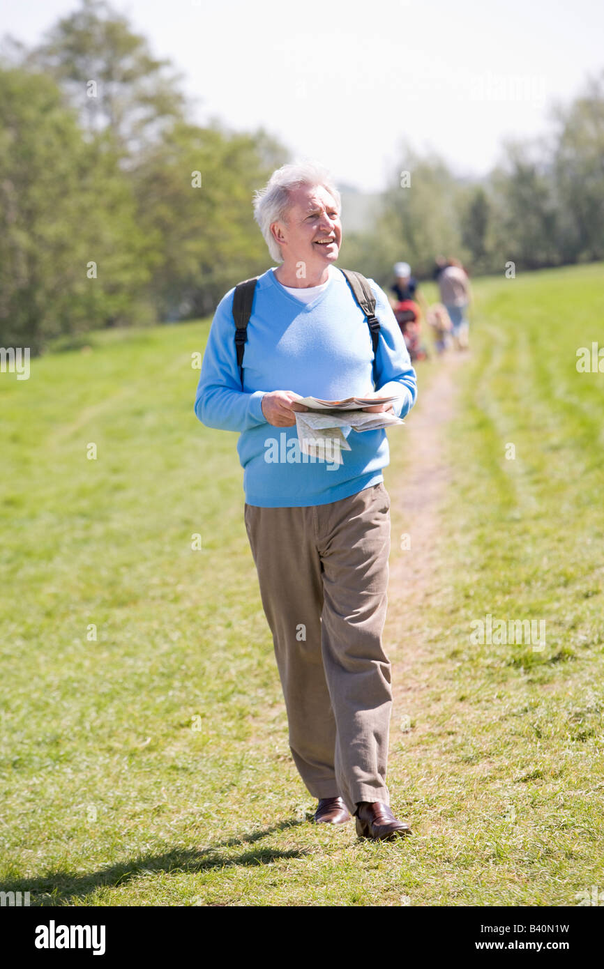 Man walking outdoors holding map smiling with people in background ...