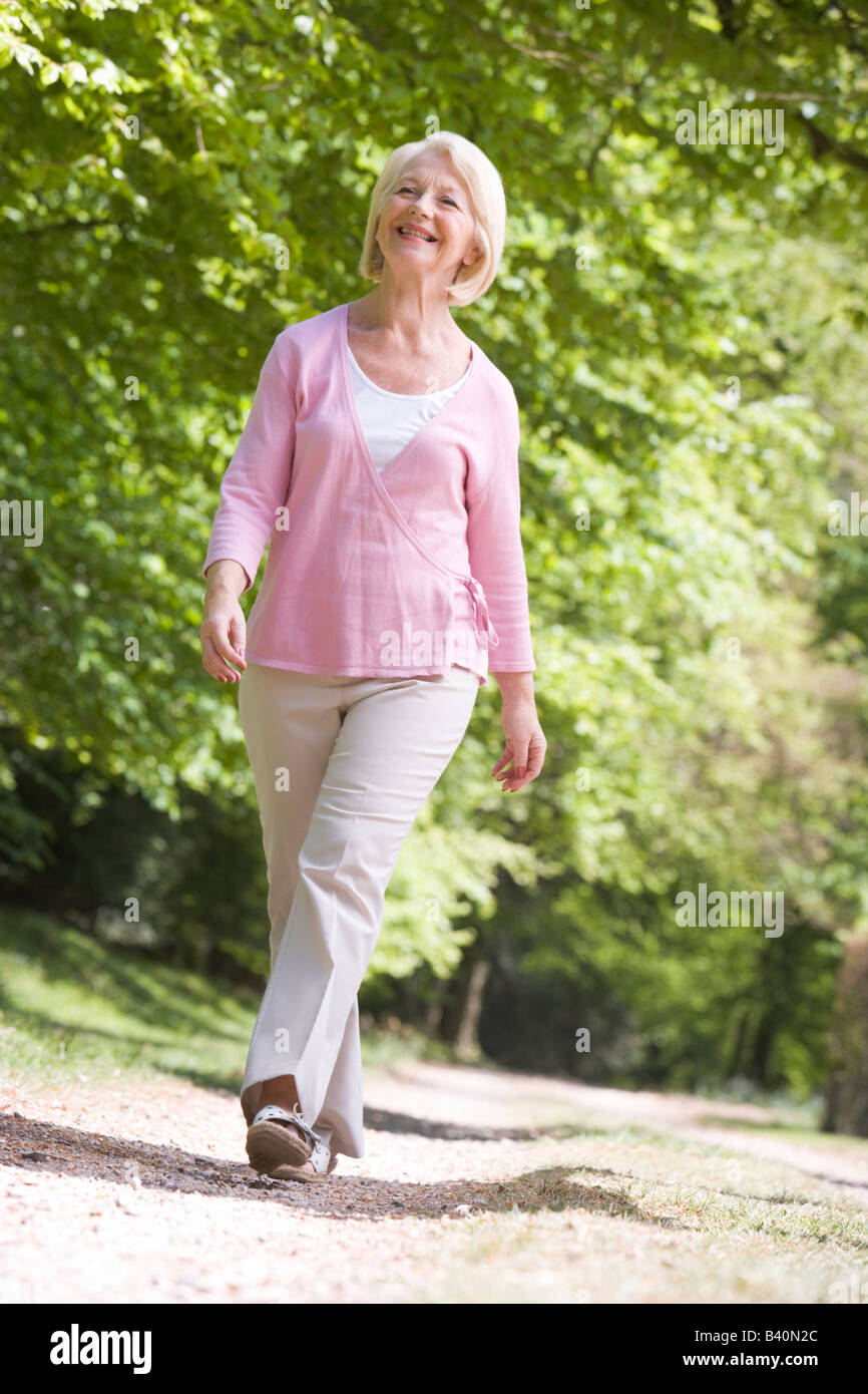 Woman walking outdoors smiling Stock Photo - Alamy
