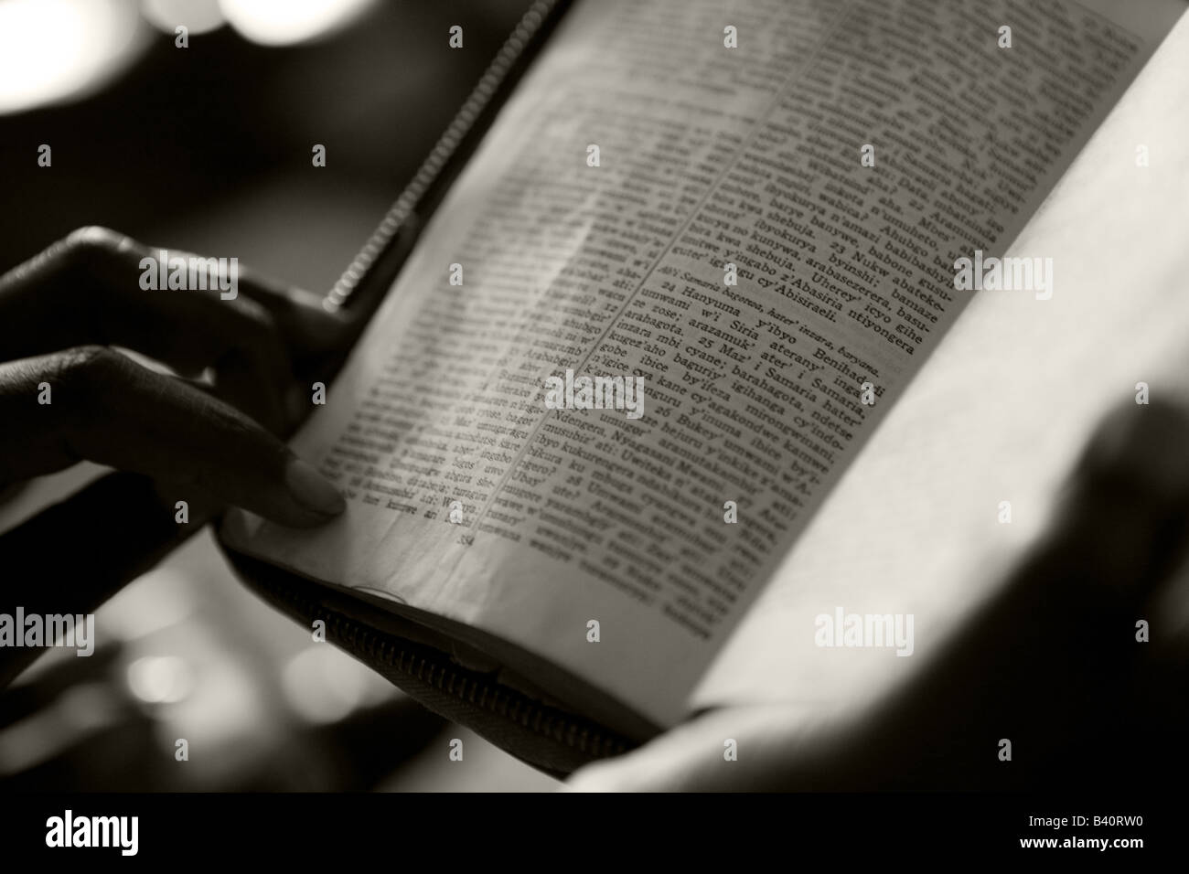 A Rwandan pastor flips through his Bible at a rural church service ...
