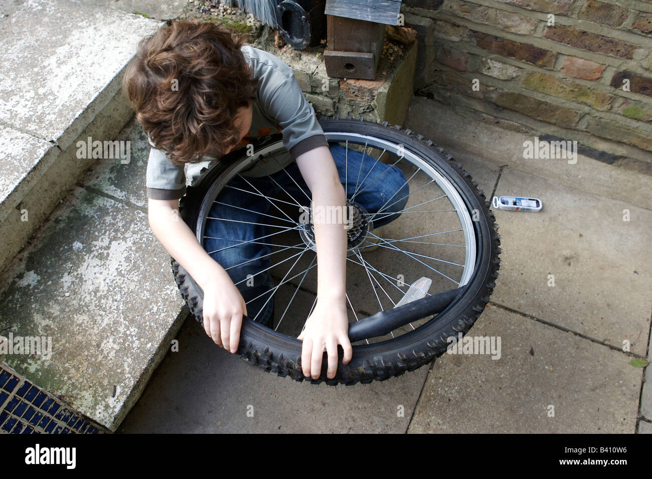 Boy fixing a puncture on his bicycle, refitting the inner tube Stock ...