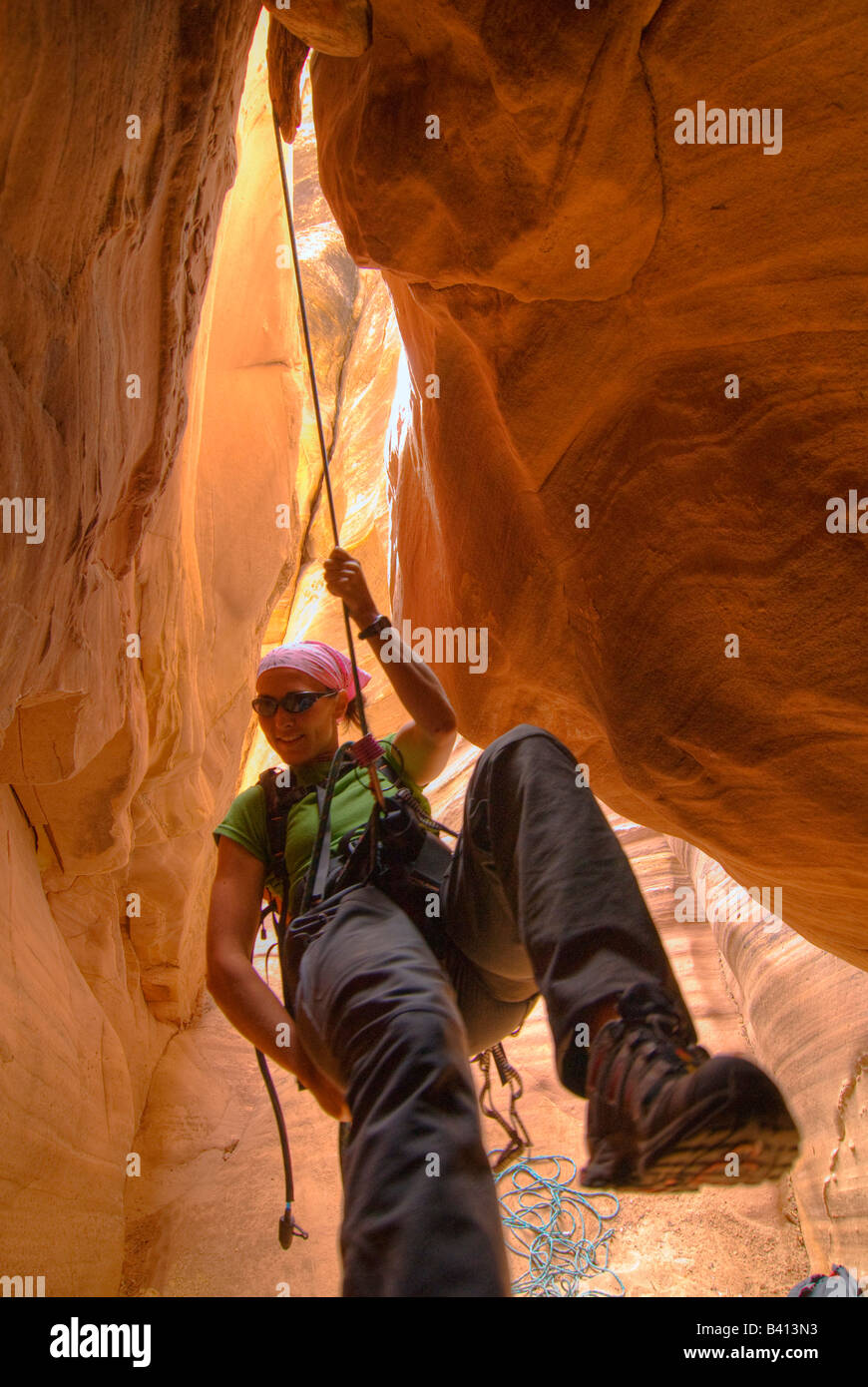 USA, Utah. A female canyoneer rappeling in Chute Canyon on the San ...