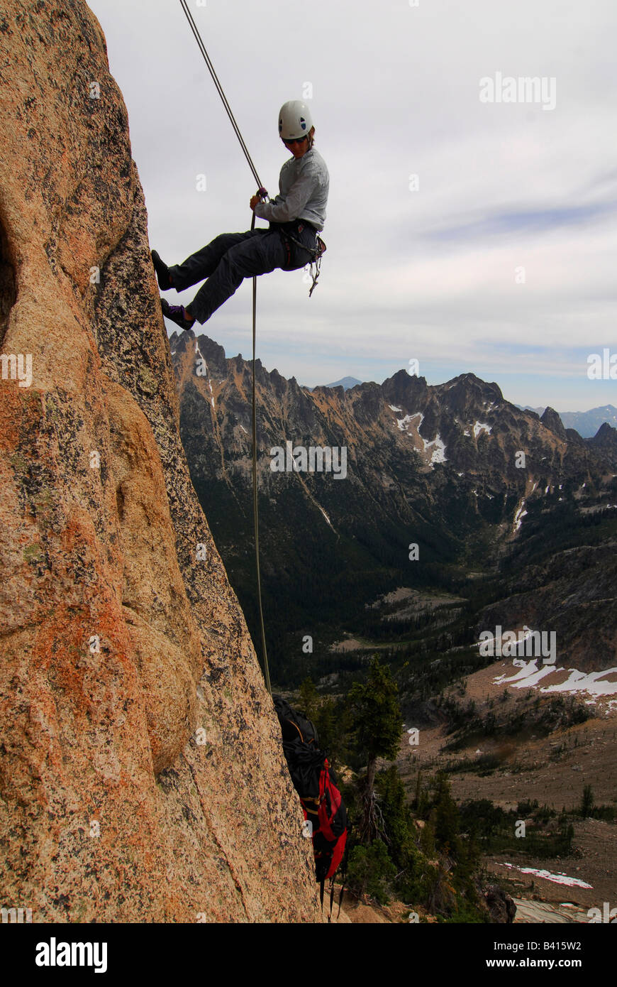 USA, Washington, Washington Pass. A female rock climber rappels to the ...