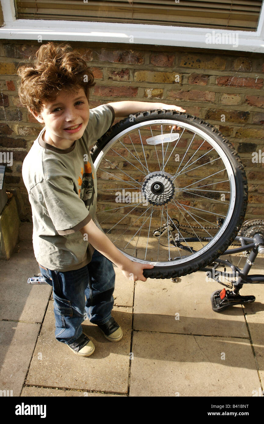 Boy fixing a puncture on his bicycle. Holding the fixed wheel Stock ...