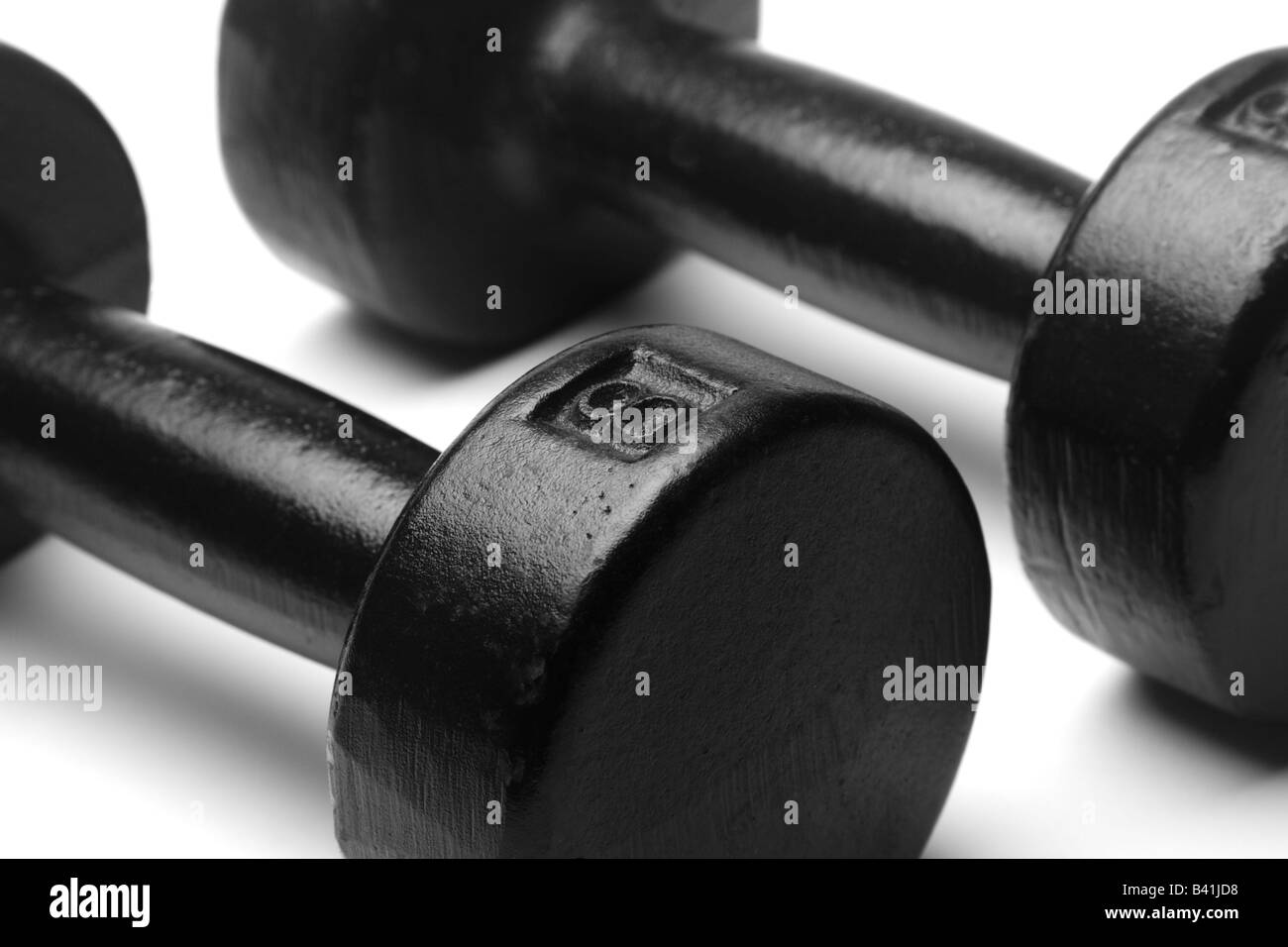 Partial view of two black exercise hand barbells, weights, stamped with ...