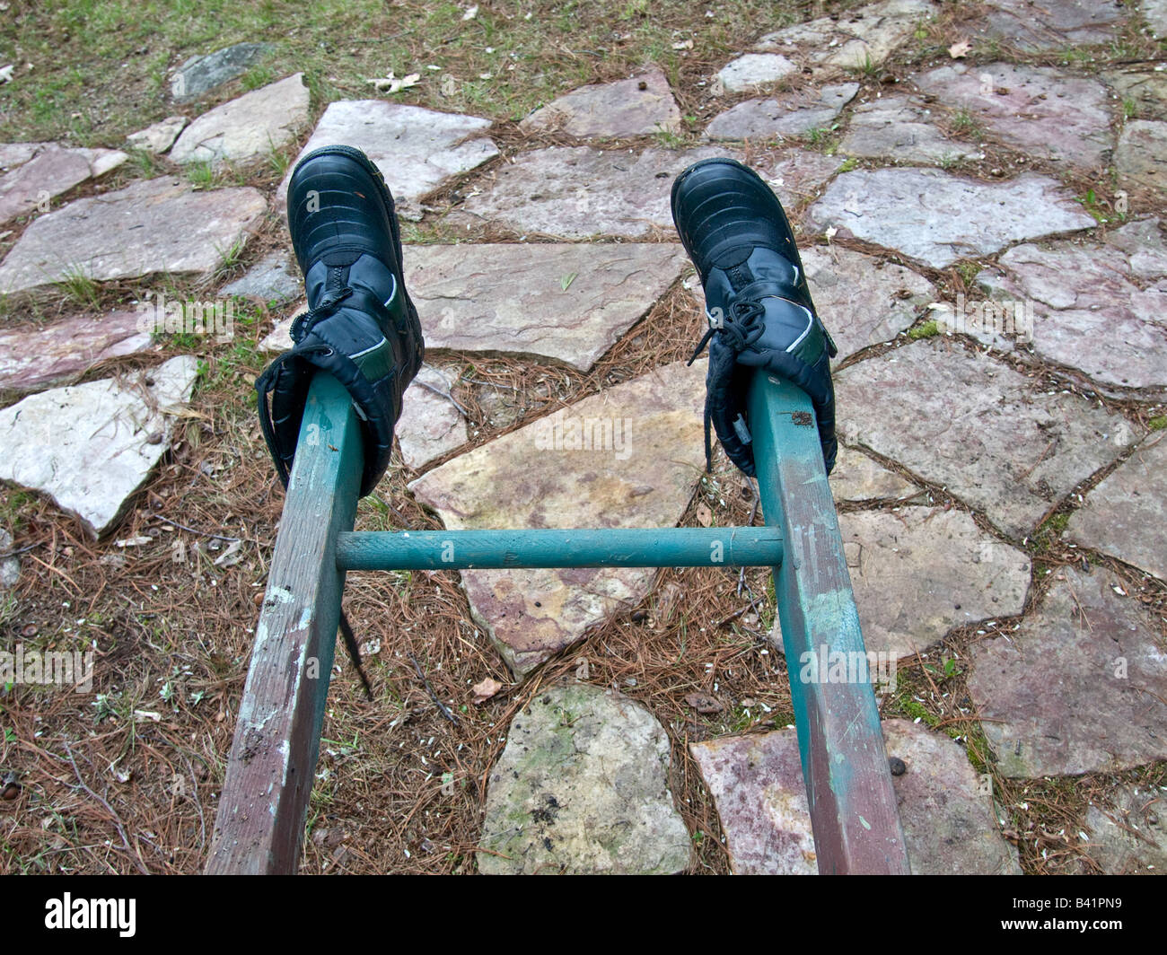 A pair of child's wet boots stuck on the end of a rustic wooden ladder ...