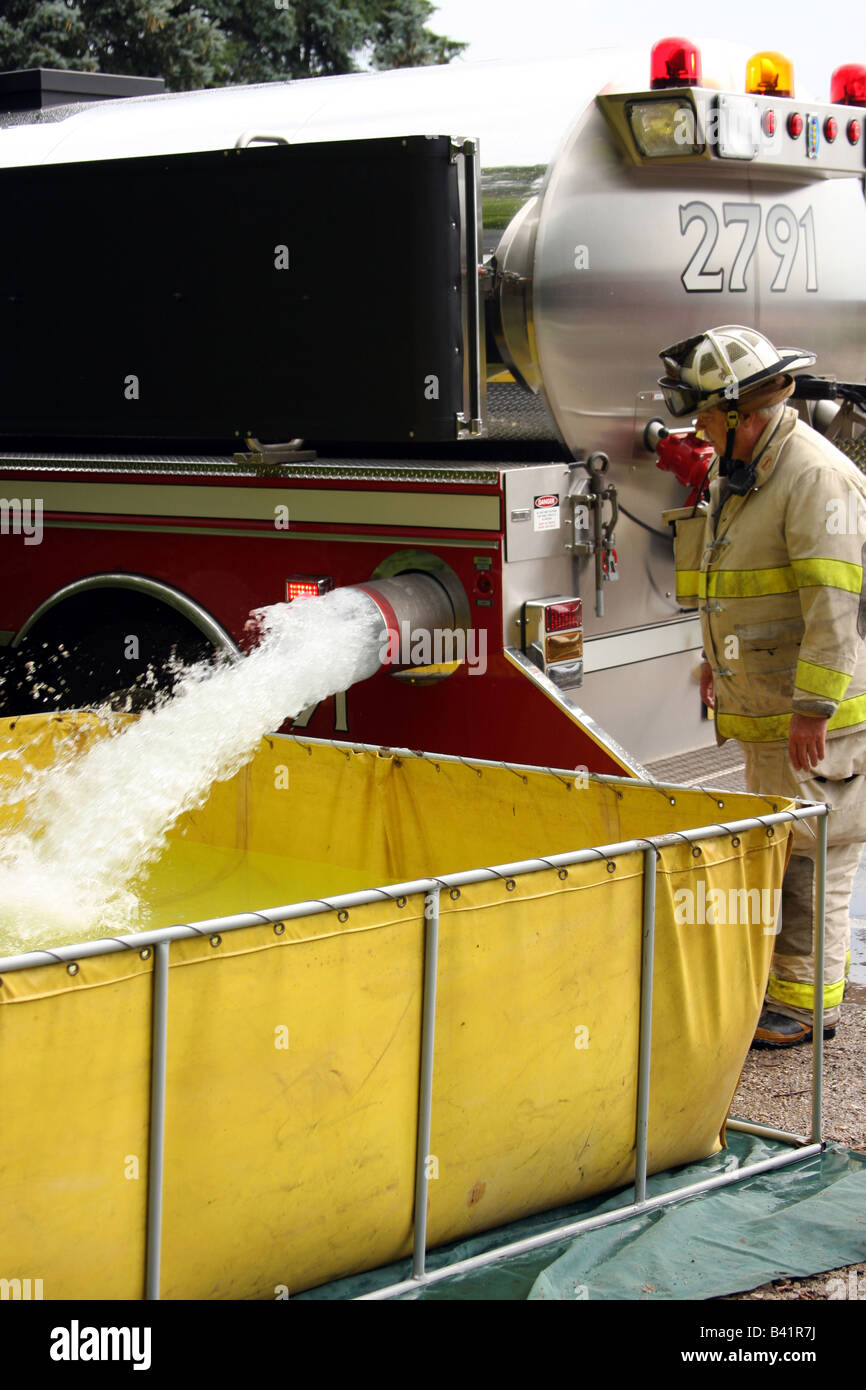 A tanker filling a canvas holder with water at a rural emergency fire ...