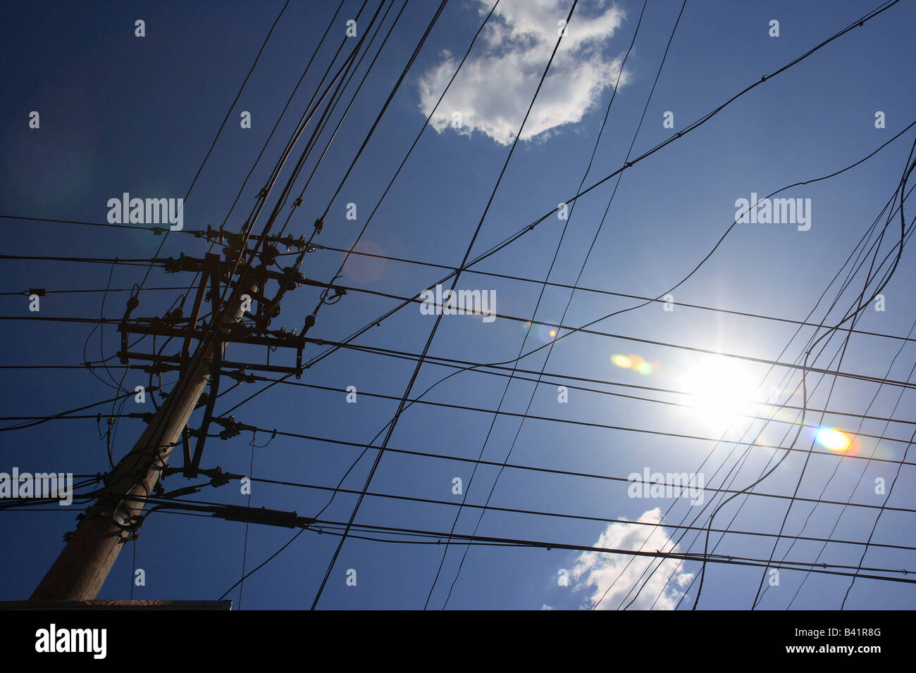 Power lines against blue sky Stock Photo - Alamy