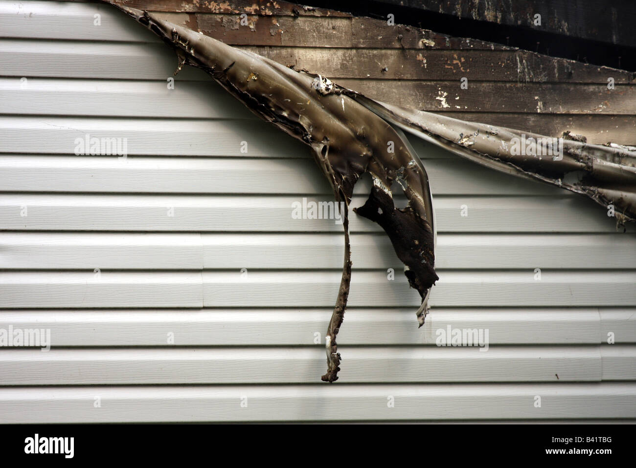The damaged siding on the garage that has melted due to the intense ...