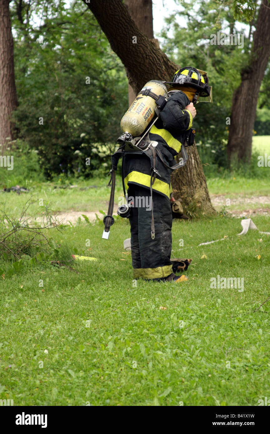 A women firefighter putting on the air pack at a emergency fire scene ...
