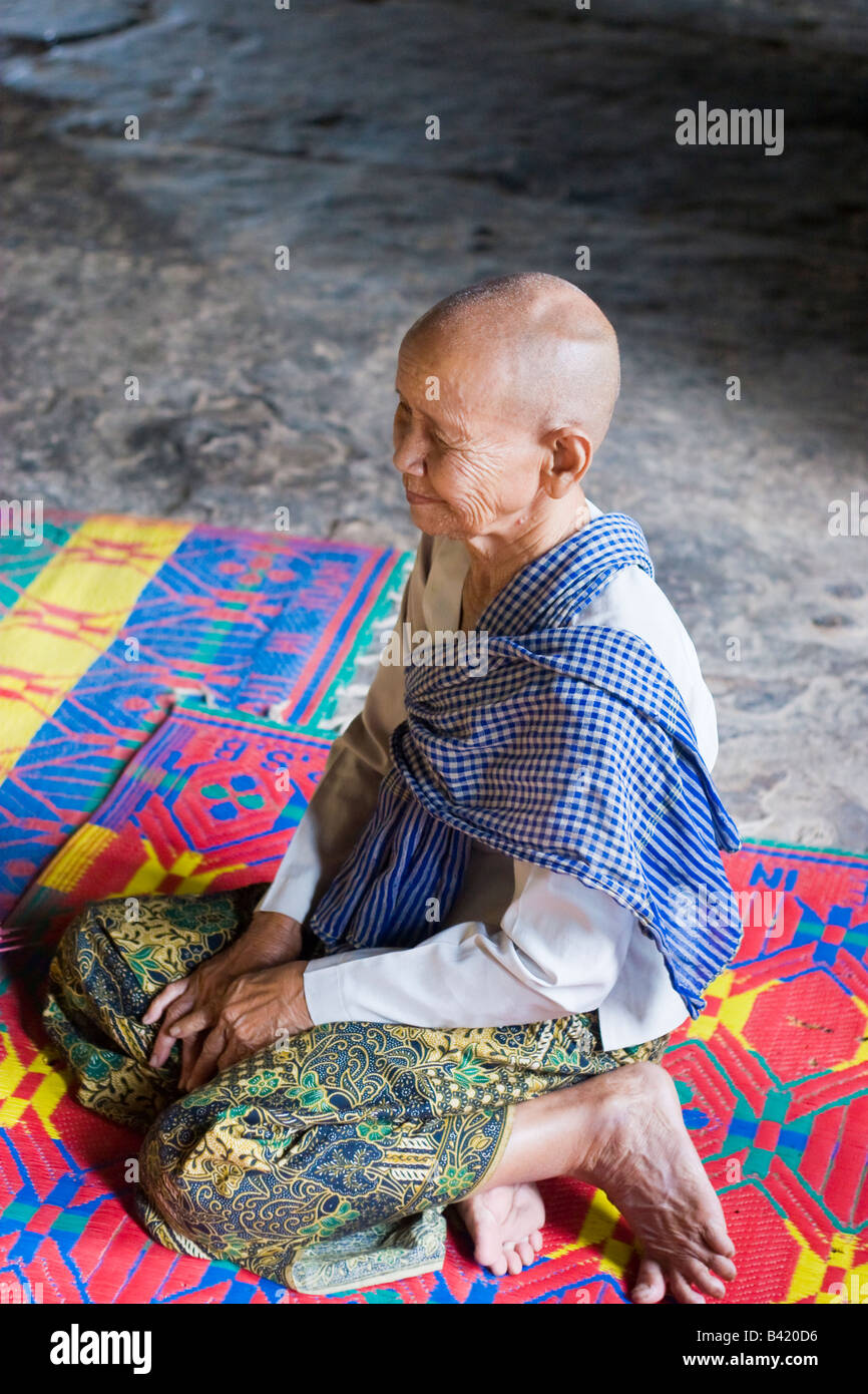 Elderly Cambodian Khmer woman kneeling on colorful ground covering ...