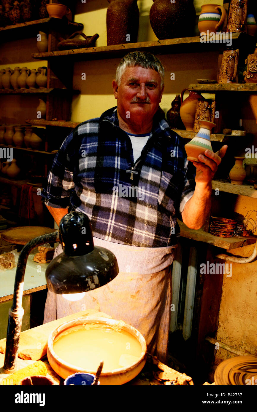 Old ceramic artist smiling and showing his product and looking at ...
