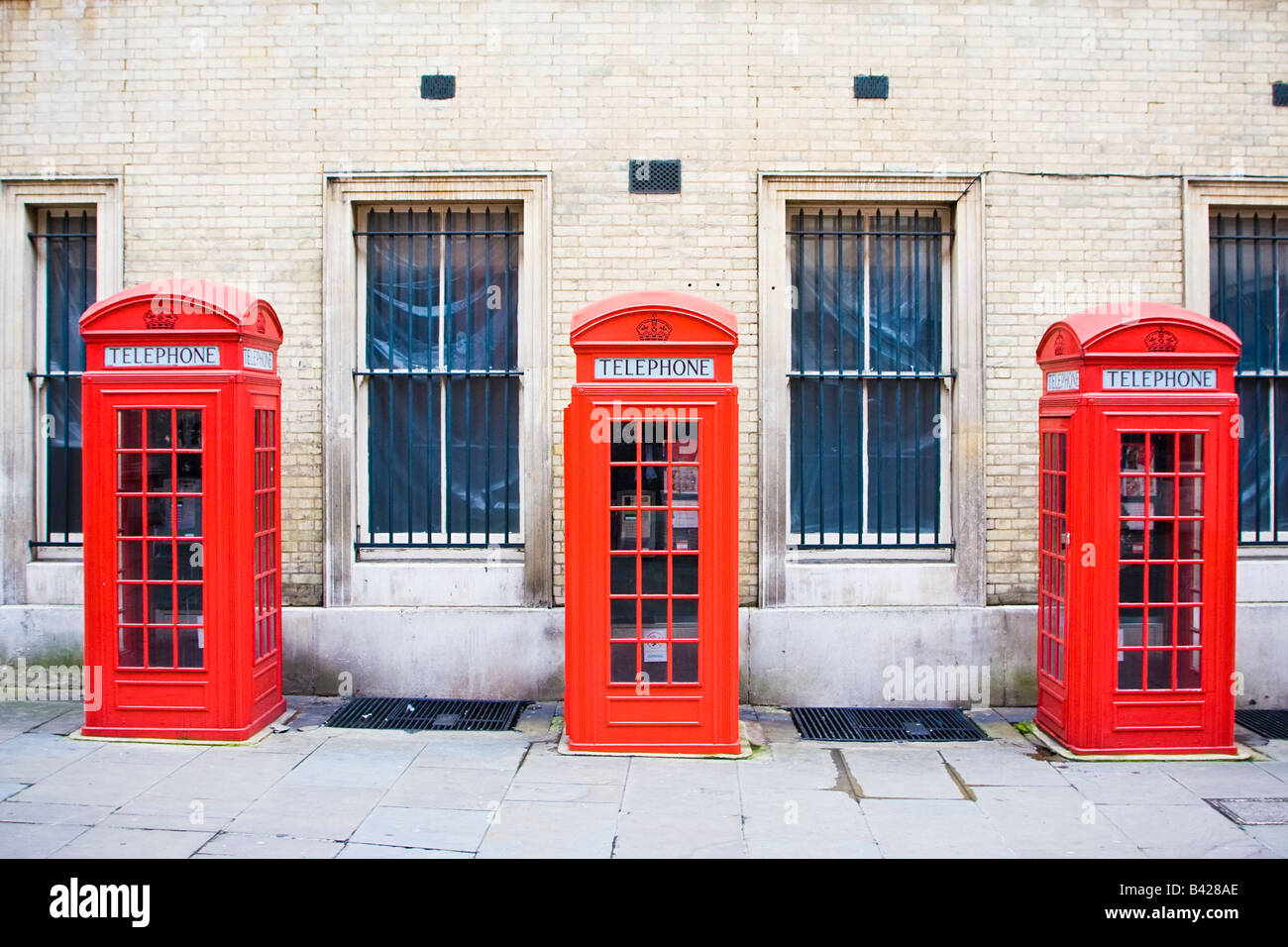 Three red phone boxes over grunge wall background Stock Photo - Alamy