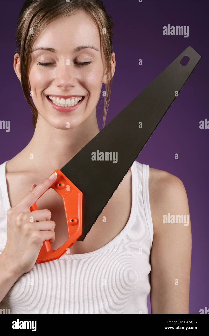 Female model eyes shut holding a saw Stock Photo - Alamy