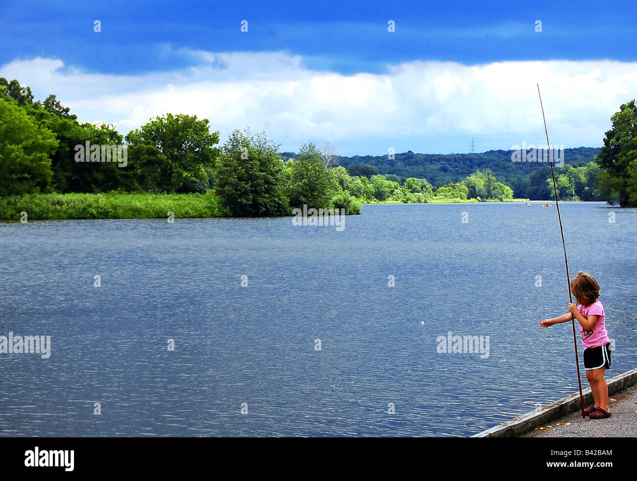 Little girl on a peer fishing by herself in a large lake Stock Photo ...
