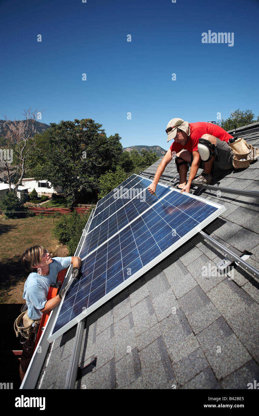 Two men installing an array of solar panels on the roof of a home Stock ...
