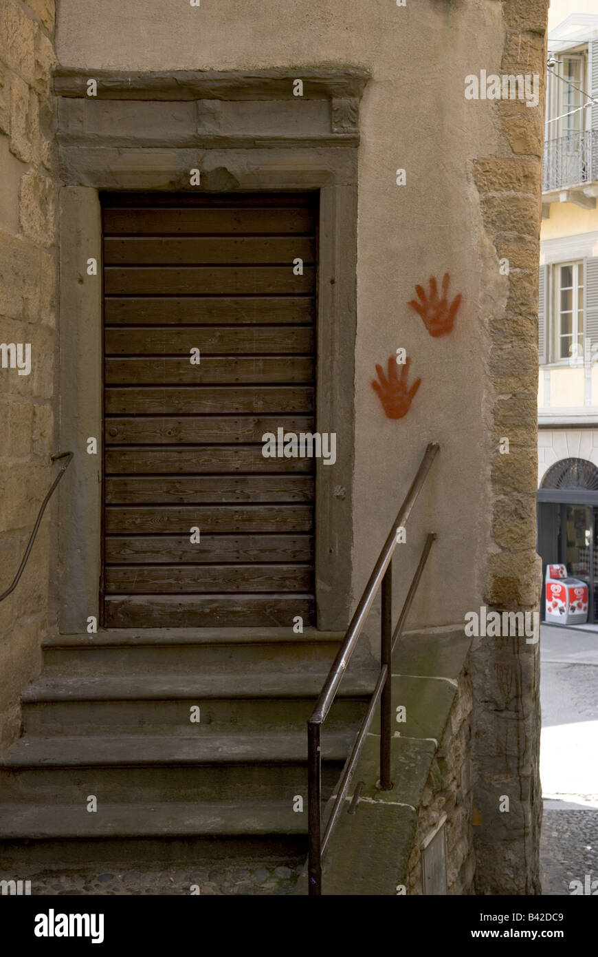 graffiti of two red hands next to old door in central bergamo, italy ...