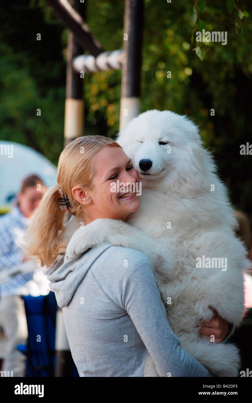 A blond young woman kissing and hugging her samoyed dog Stock Photo - Alamy