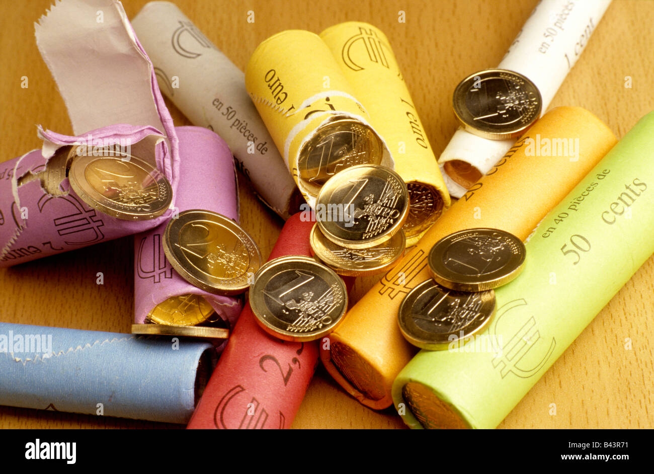 Coins and wrapped rolls of currency on wooden surface showcasing one ...