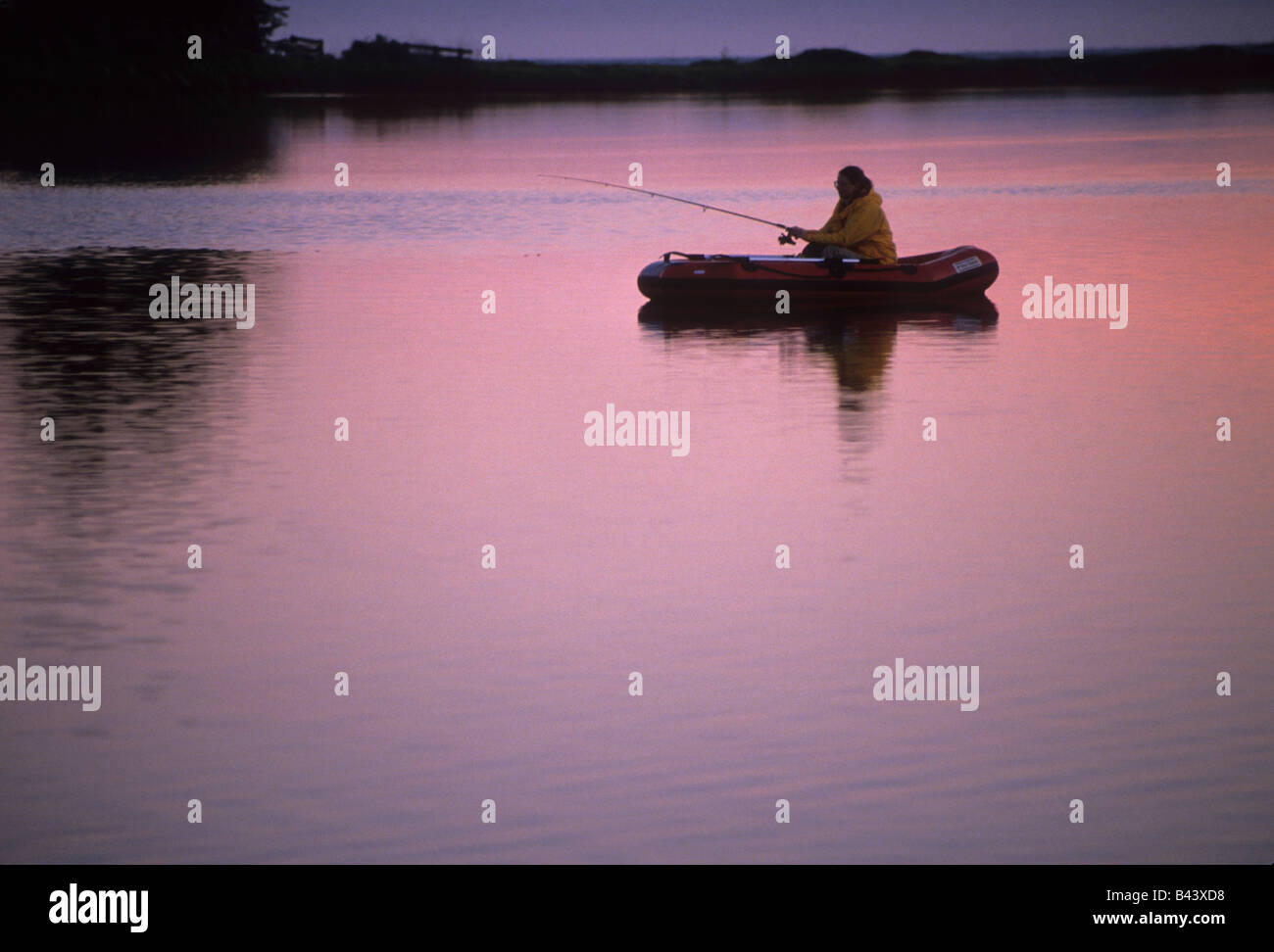 Person in boat on lake at sunset Stock Photo - Alamy