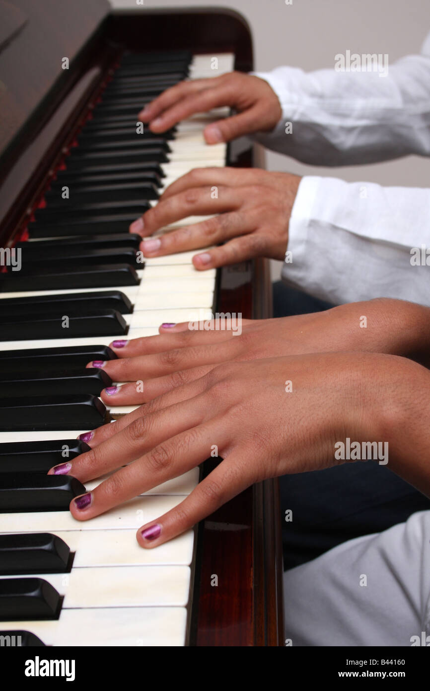 Two pairs of hands playing a piano Stock Photo - Alamy