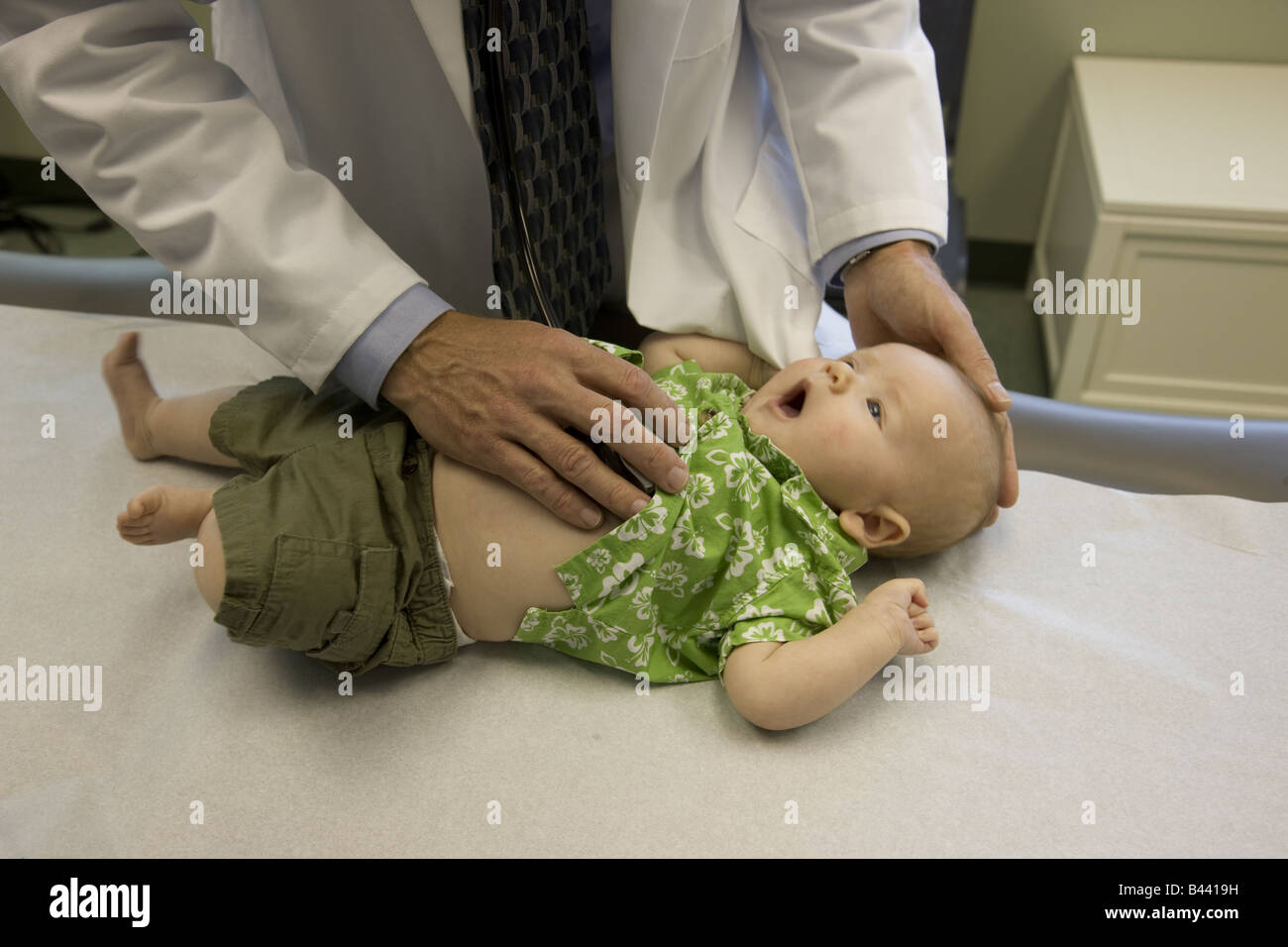 A doctor examines a baby's belly as the baby yawns Stock Photo - Alamy