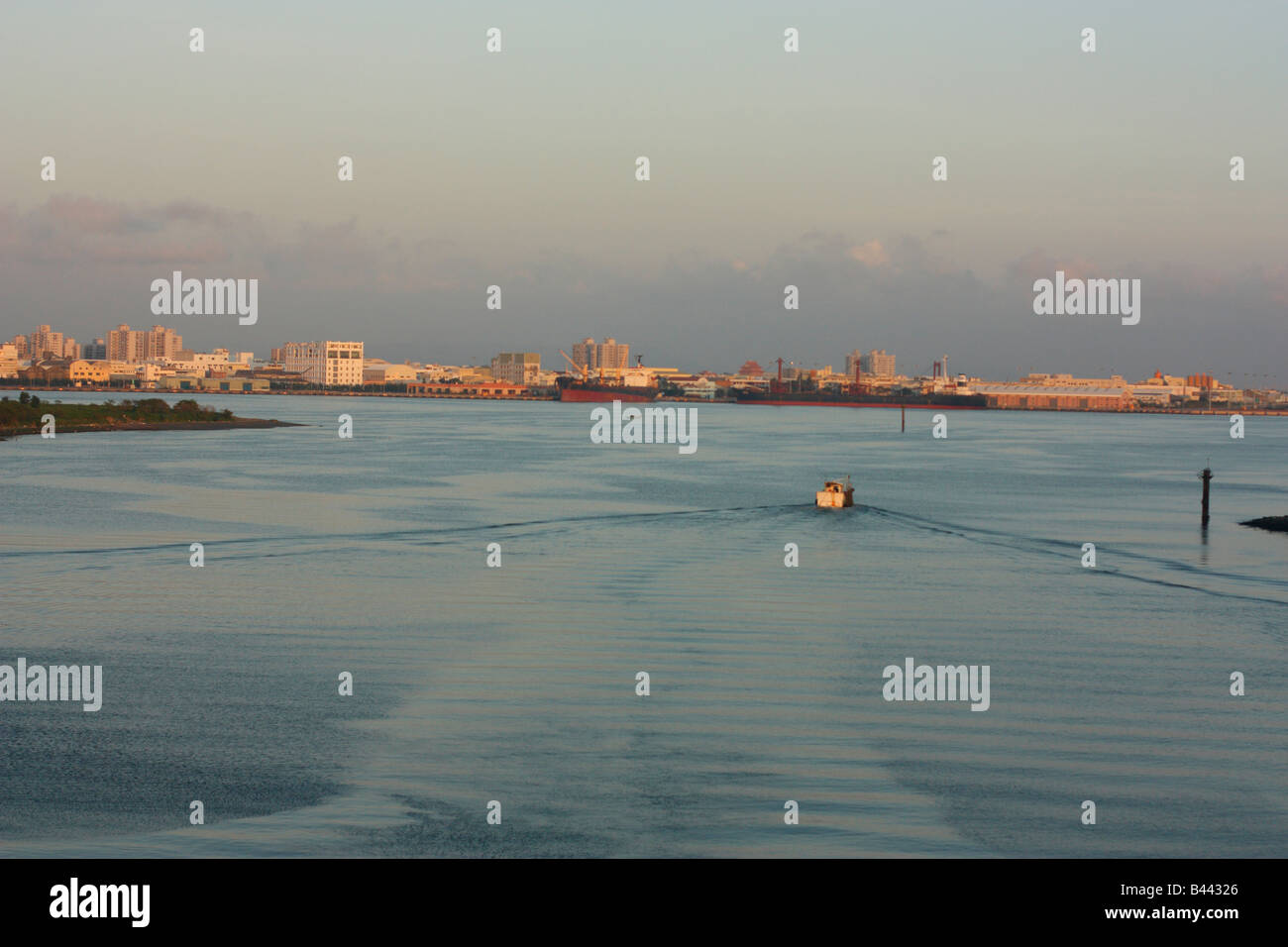 A lone fishing boat sails out of Anping Port at sunset. Tainan, Taiwan ...
