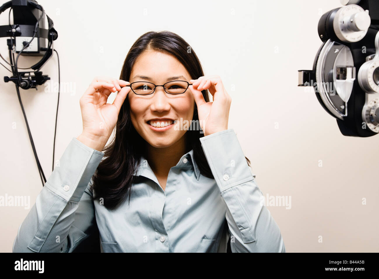 Asian woman putting on eyeglasses Stock Photo - Alamy