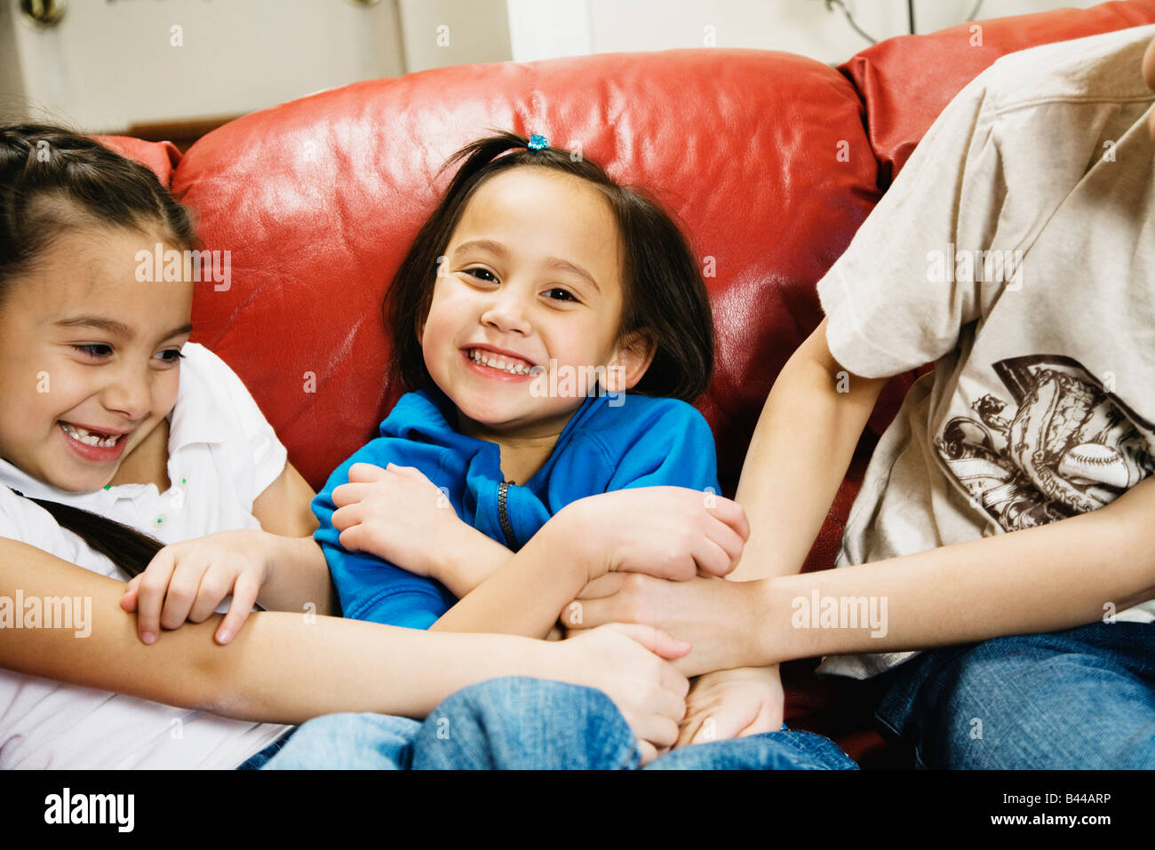 Asian siblings tickling sister Stock Photo - Alamy