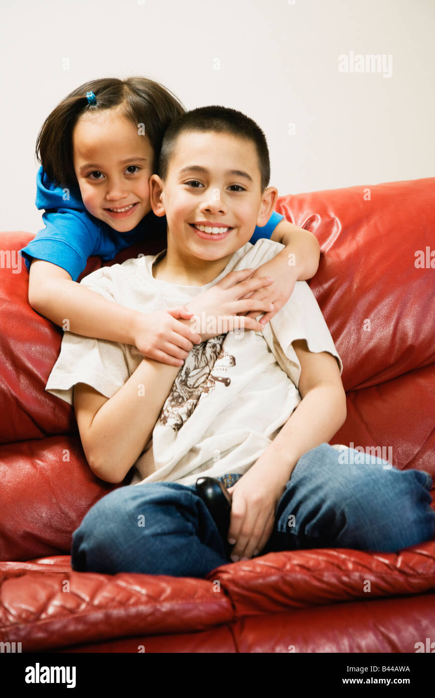 Asian siblings hugging on sofa Stock Photo - Alamy