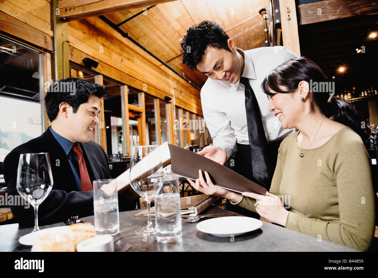 Asian couple reading menu at restaurant Stock Photo - Alamy