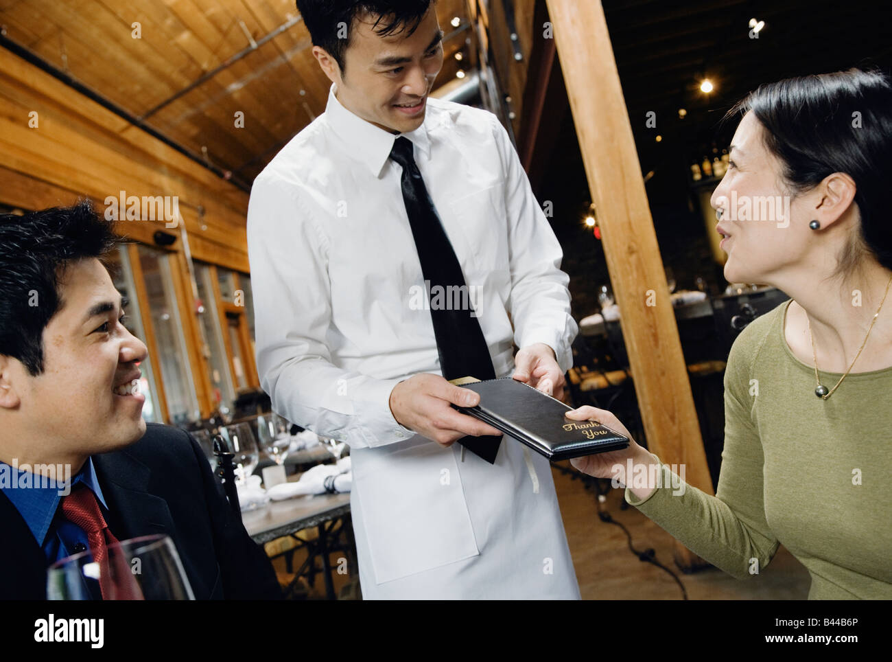 Asian couple paying restaurant bill Stock Photo - Alamy
