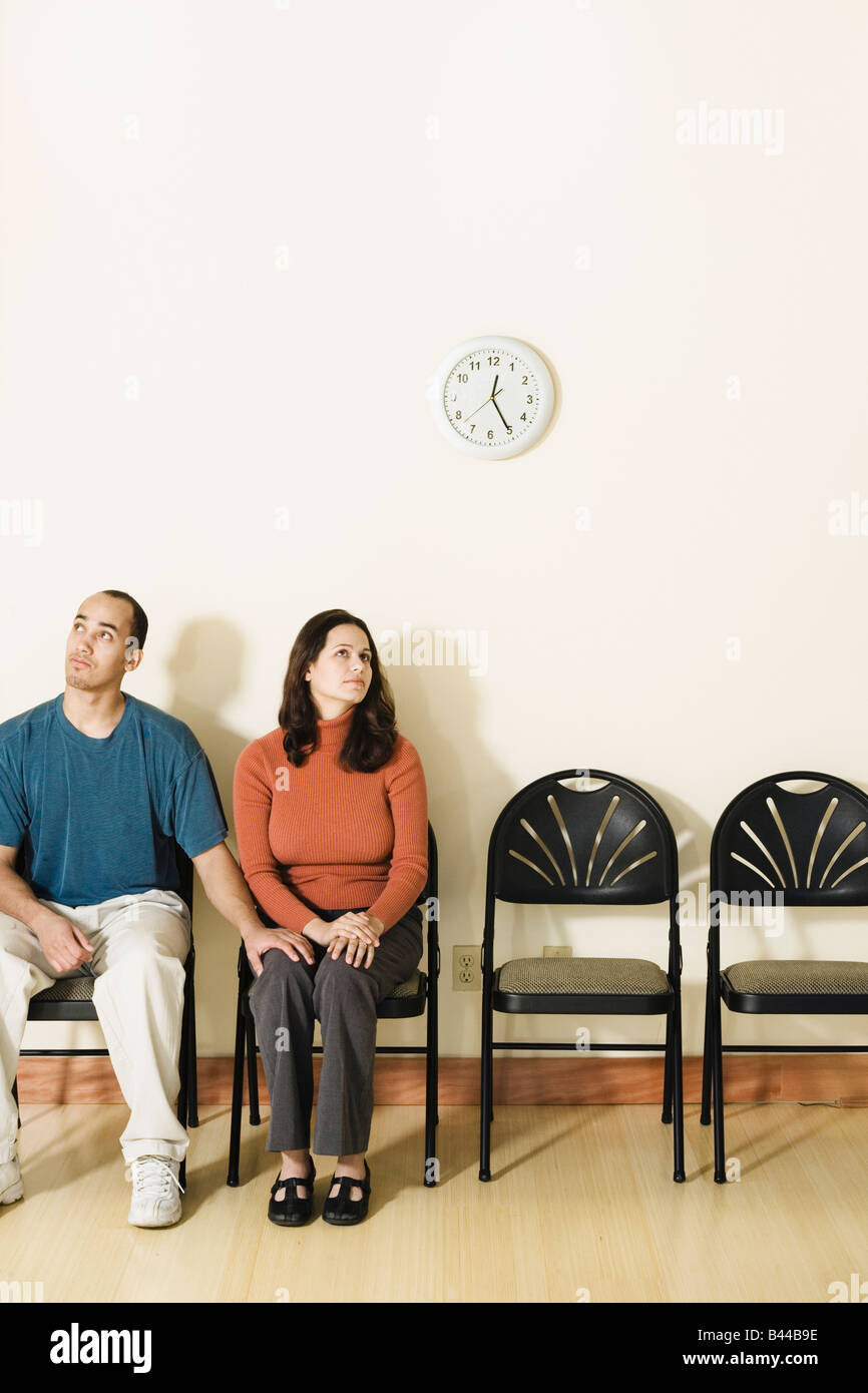Multi-ethnic couple sitting in waiting area Stock Photo - Alamy