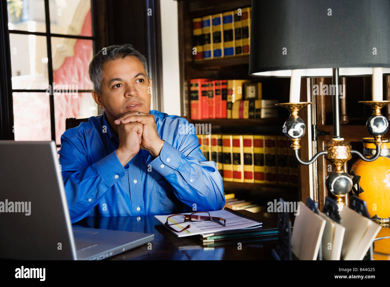Hispanic man thinking at desk Stock Photo - Alamy
