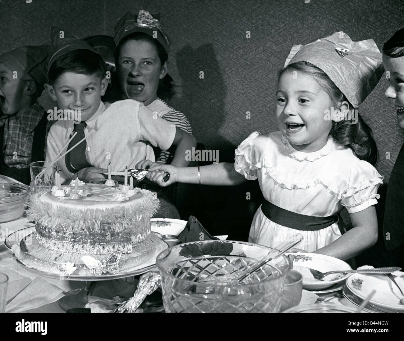 Kids pull crackers at Christmas party 1950 Infront of xmas cake and ...